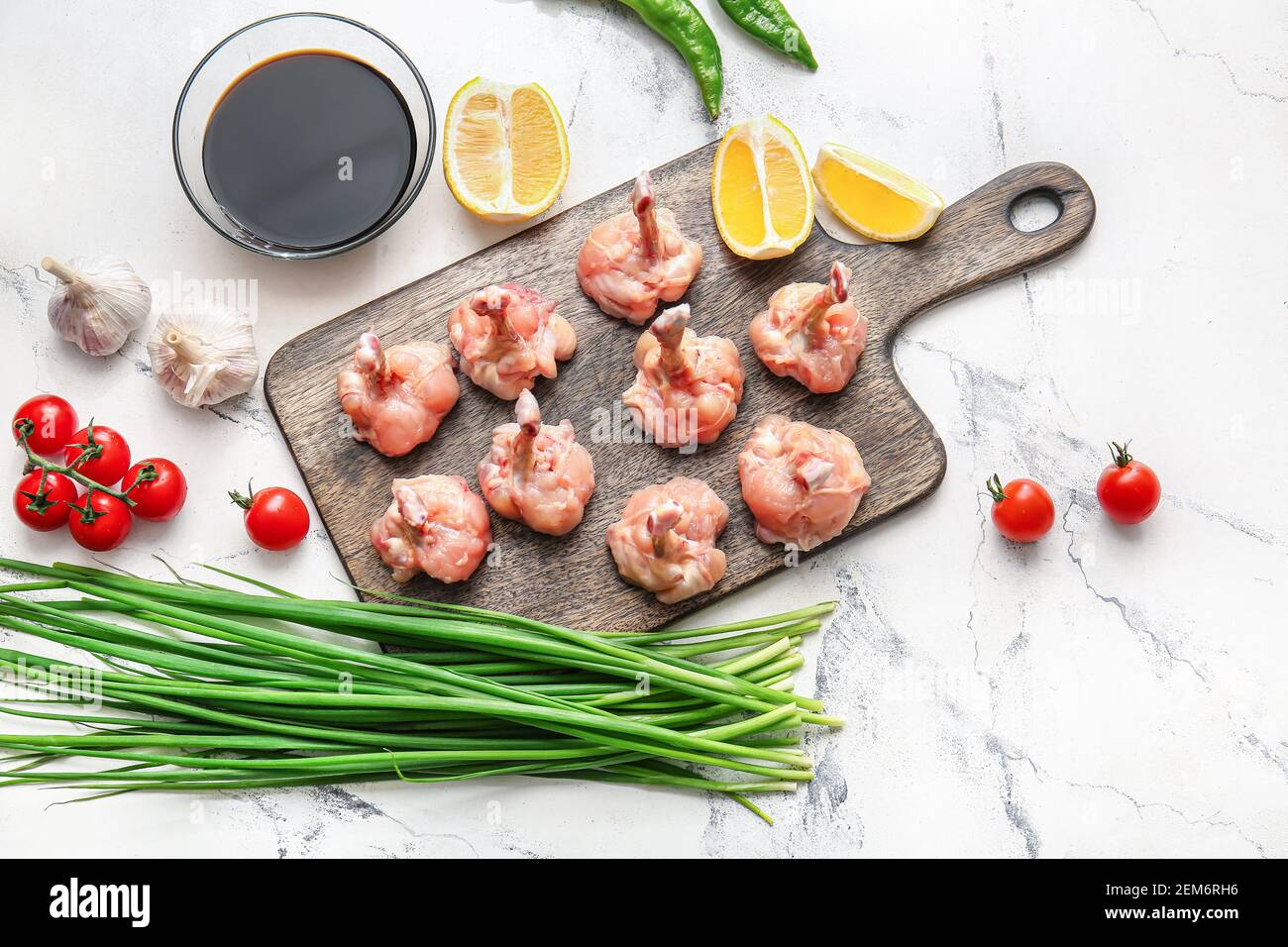 Board with raw chicken lollipops on light background Stock Photo - Alamy