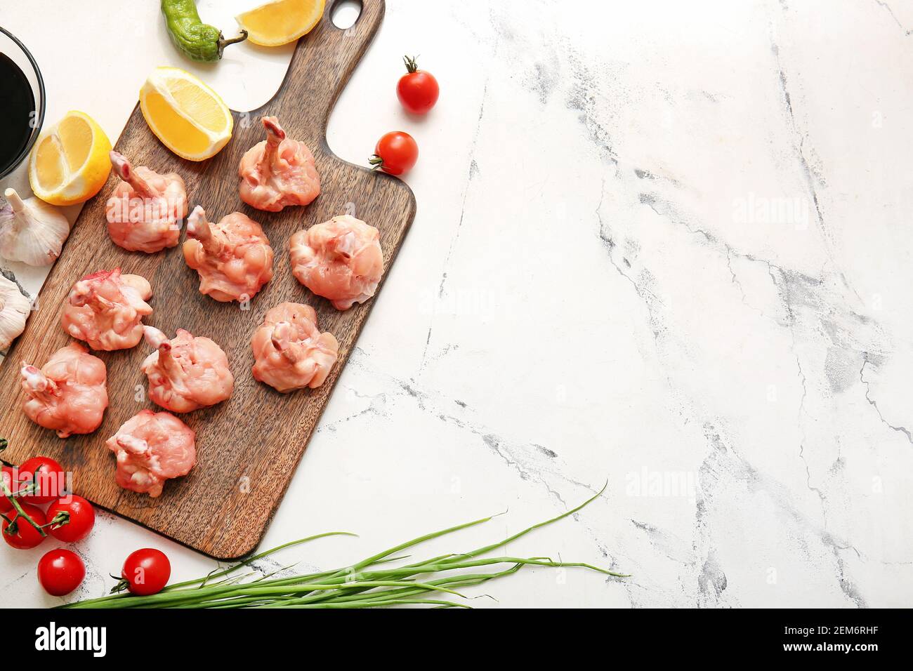 Board with raw chicken lollipops on light background Stock Photo - Alamy