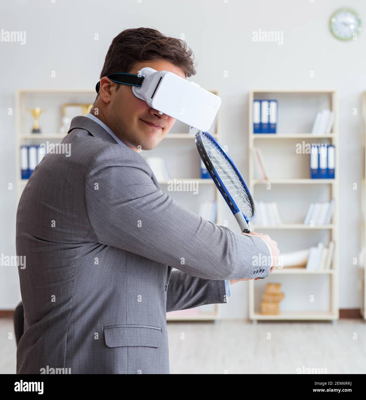 Businessman playing virtual reality tennis in office with VR goggle ...