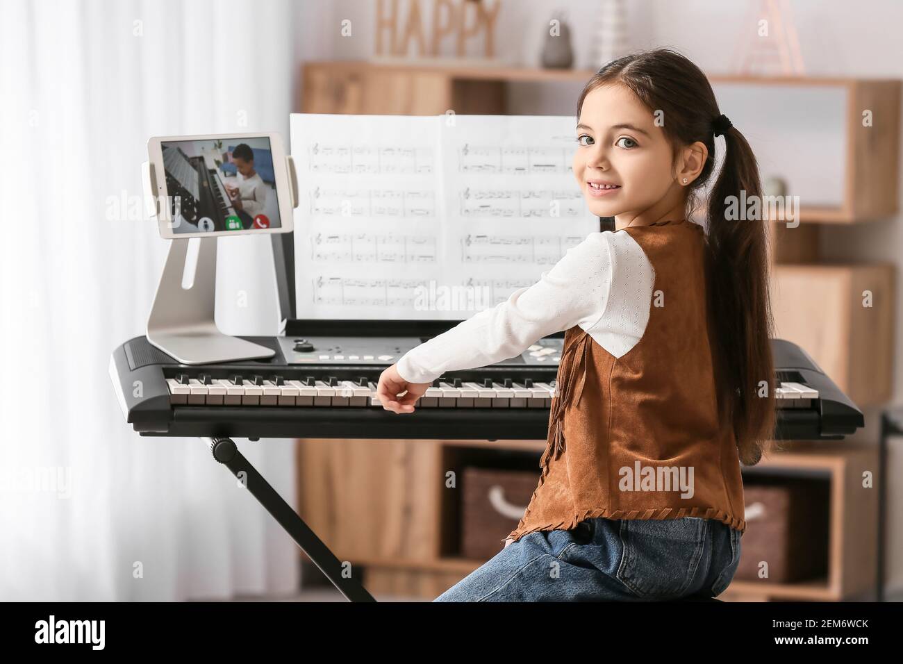 Little girl studying music with her friend online at home Stock Photo ...