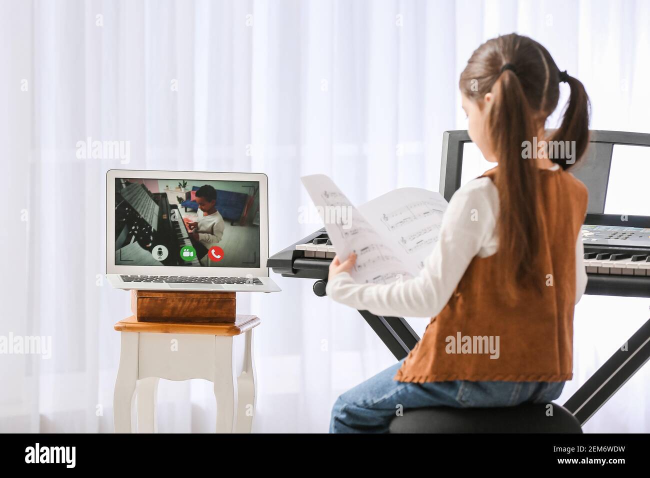 Little girl studying music with her friend online at home Stock Photo ...