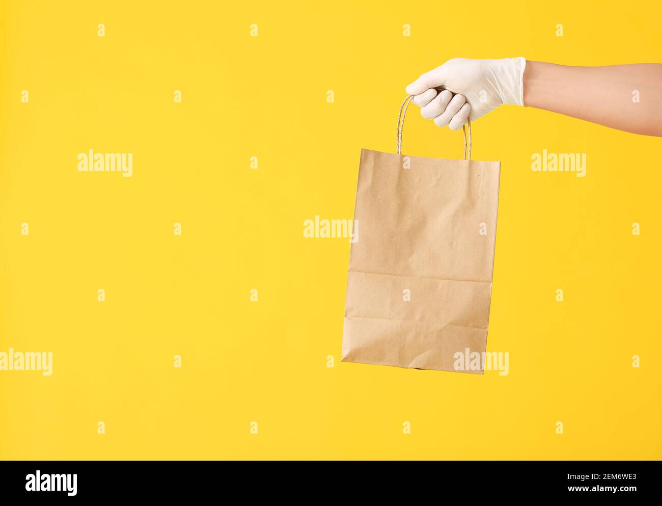 Hand of courier with paper bag on color background Stock Photo - Alamy