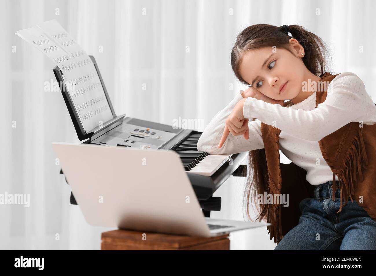 Bored little girl taking music lessons online at home Stock Photo - Alamy