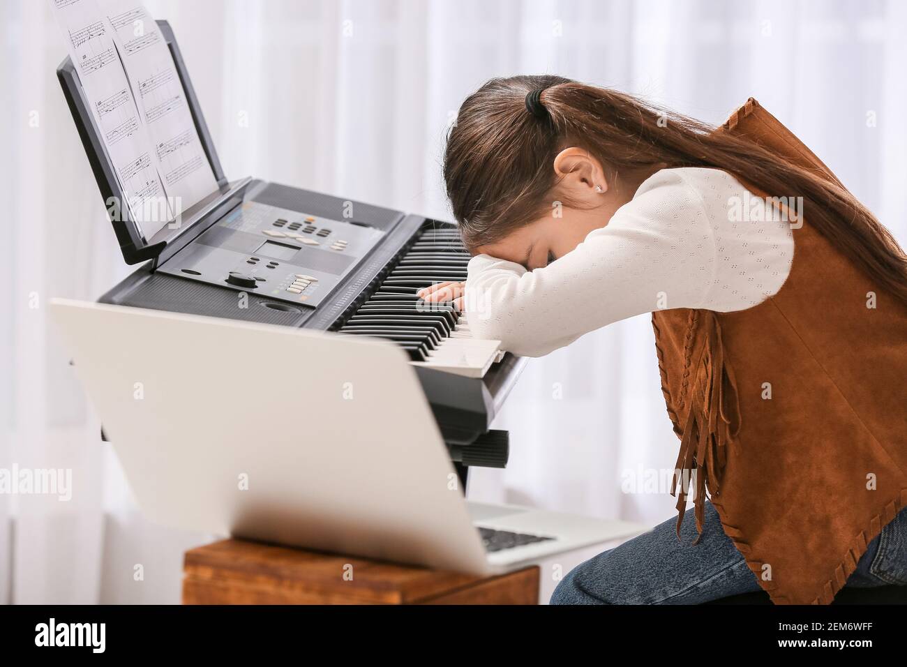 Bored little girl taking music lessons online at home Stock Photo - Alamy