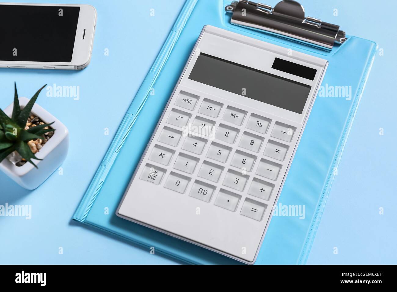 Modern calculator and clipboard with mobile phone on color background ...