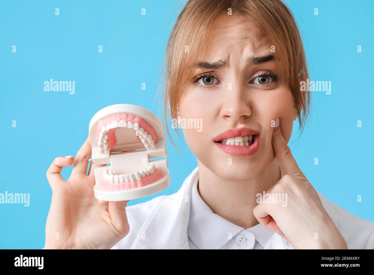 Confused dentist with plastic jaw model on color background Stock Photo ...