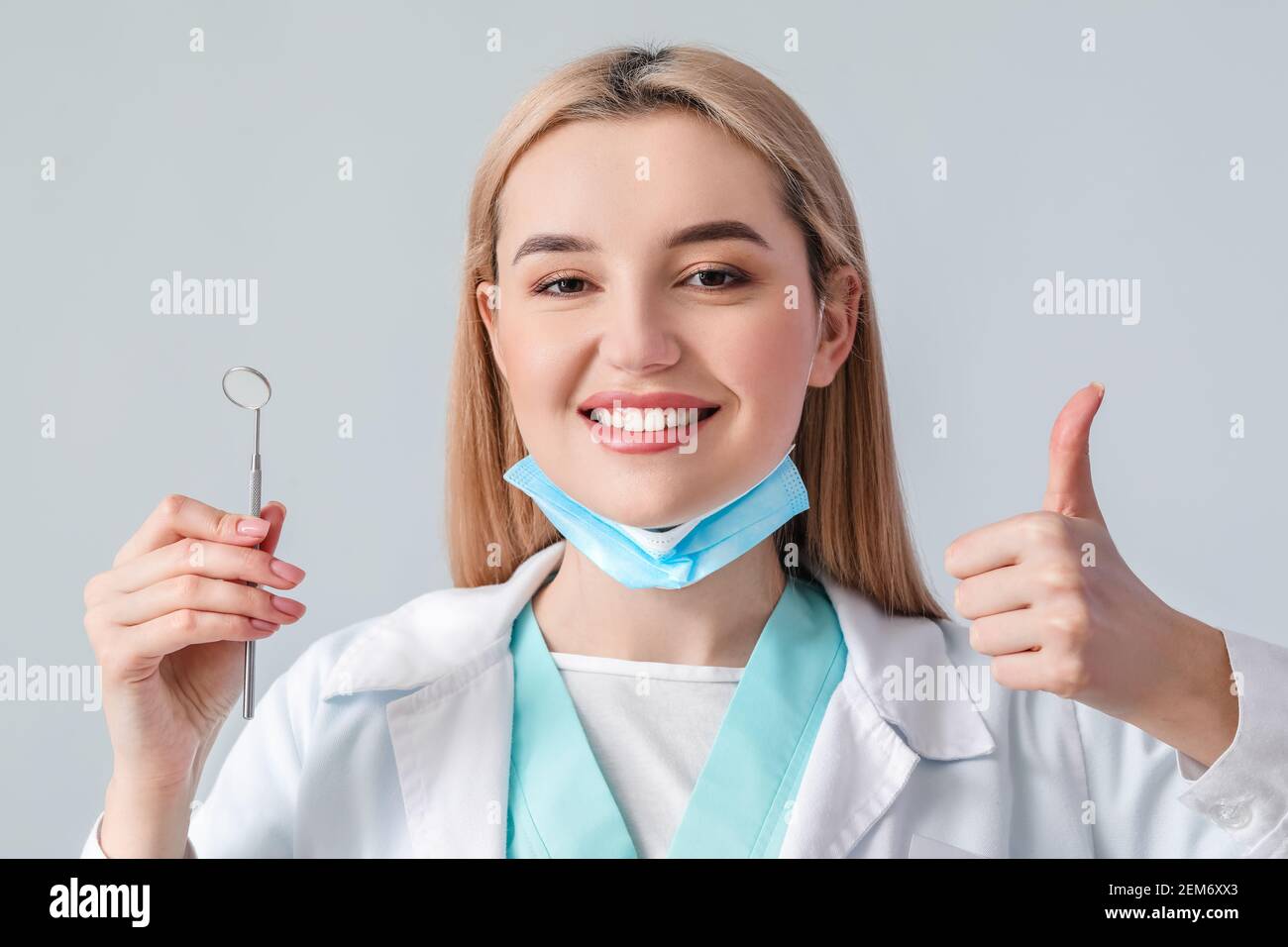 Female dentist showing thumb-up on light background Stock Photo - Alamy