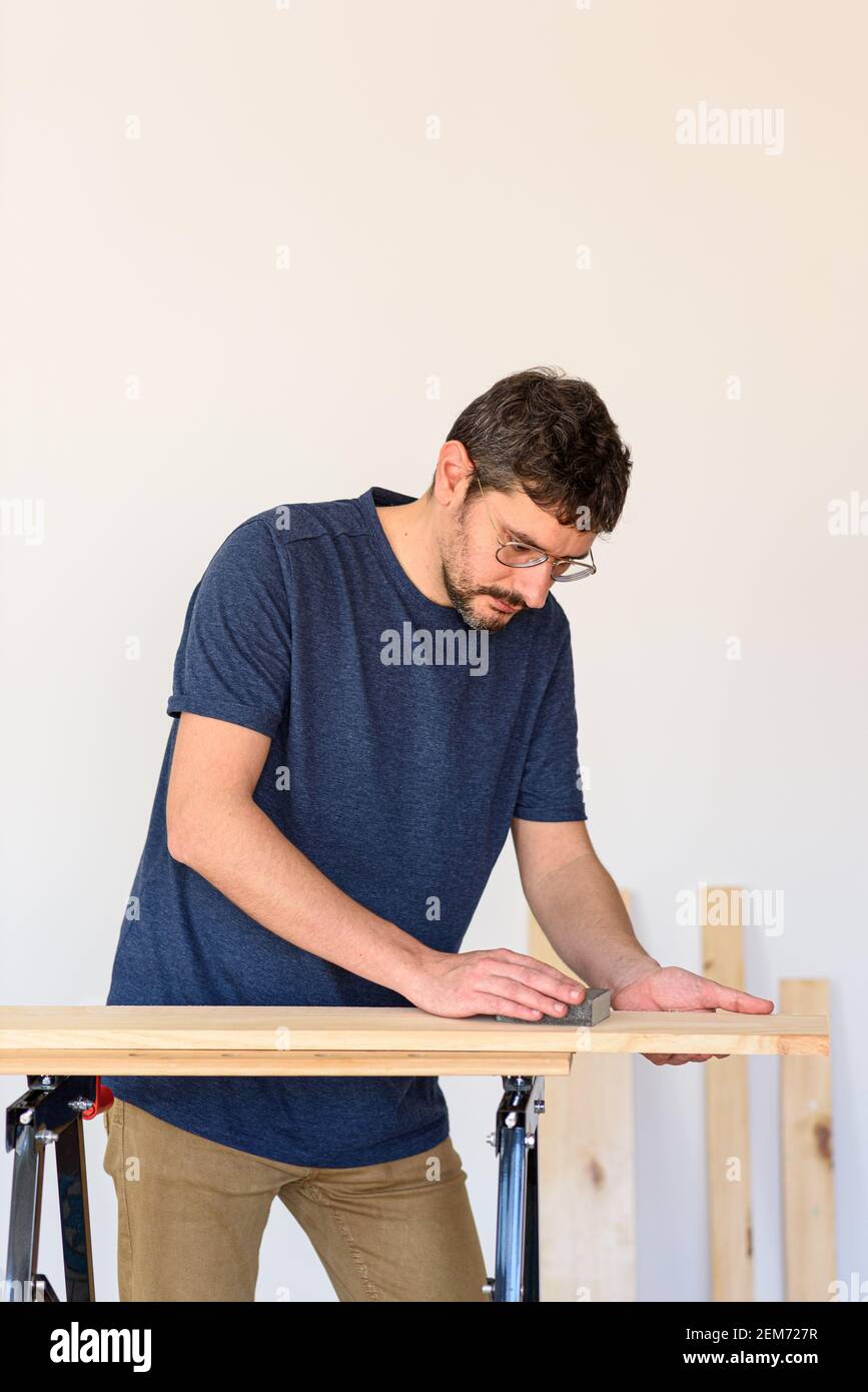 Man at home sanding a wood on a workbench. White background Stock Photo ...