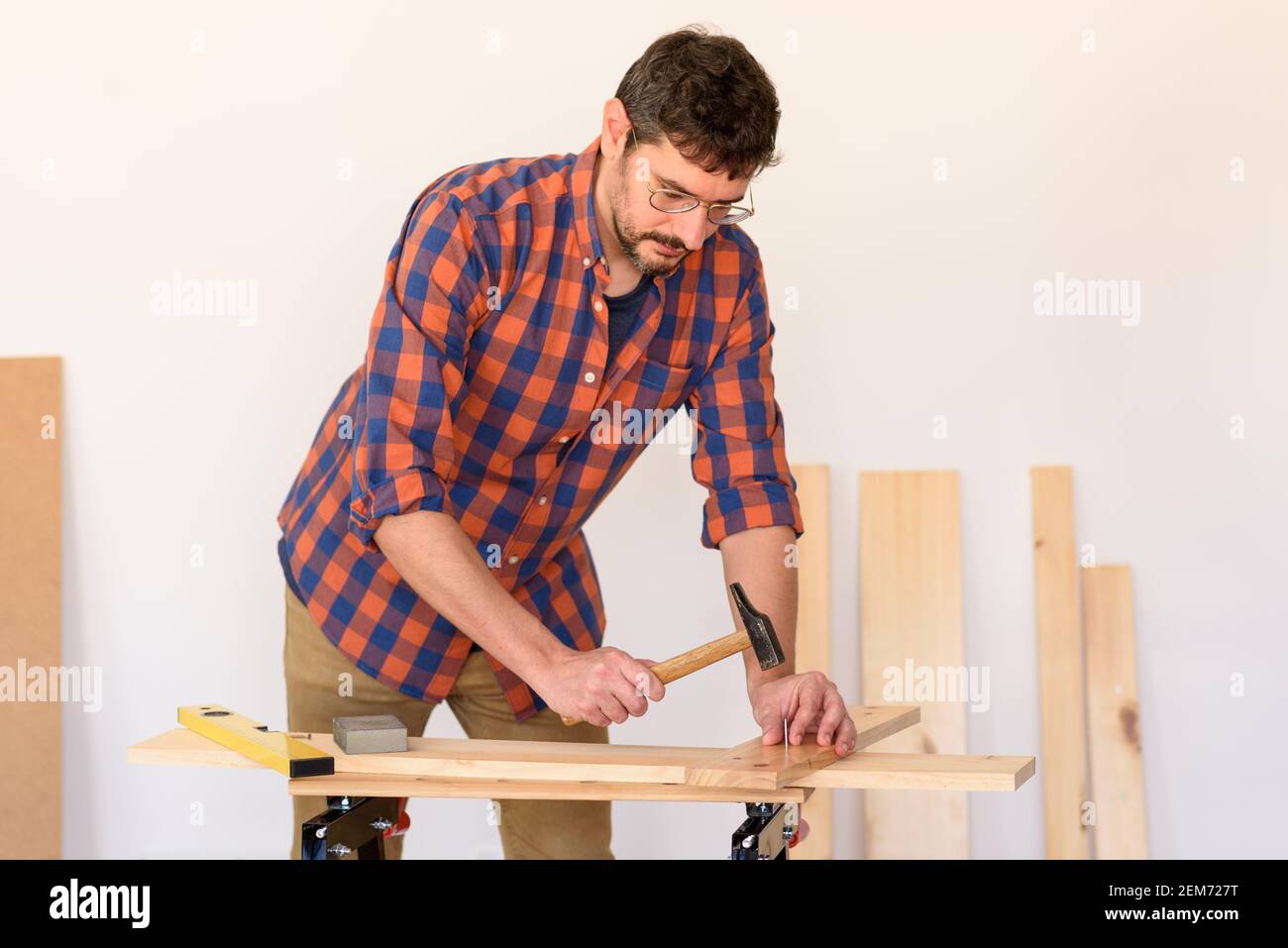 Man driving a nail into a table on a workbench. High quality photo ...