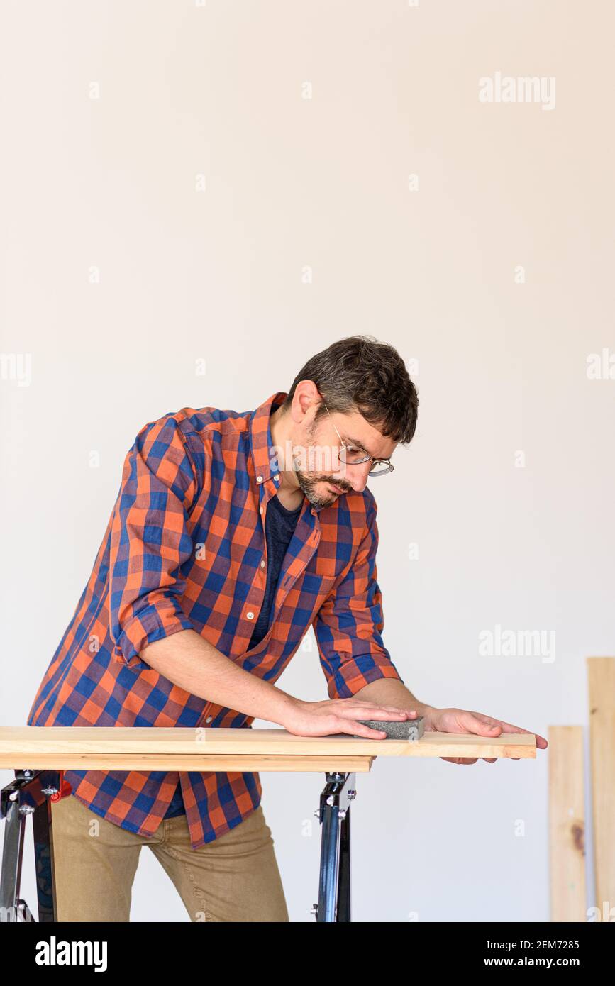 Man at home sanding a wood on a workbench. White background Stock Photo ...