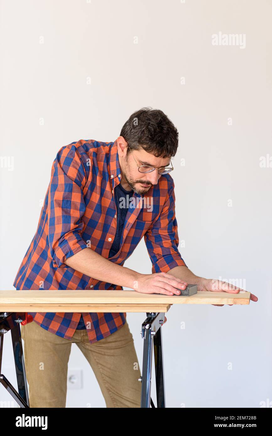 Man at home sanding a wood on a workbench. White background Stock Photo ...