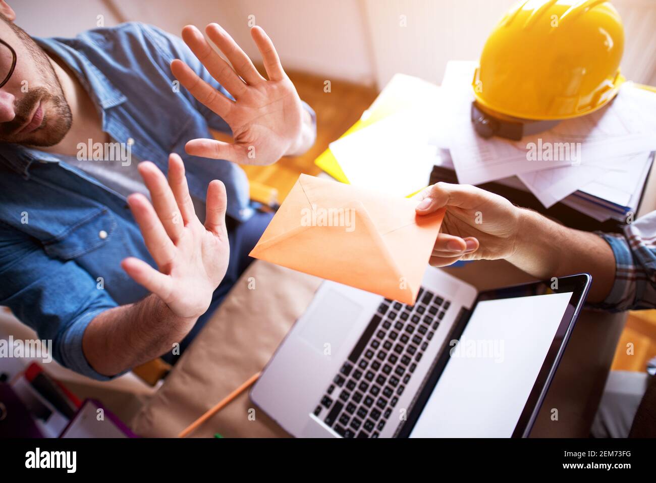 Young businessman is refusing a bribe in the envelope over the laptop ...