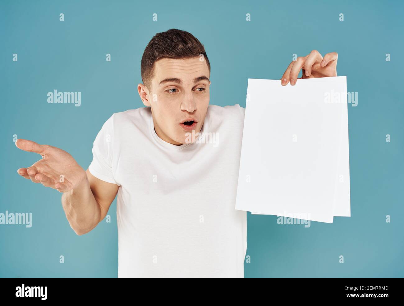 Male advertiser with a white sheet of paper on a blue background mockup ...