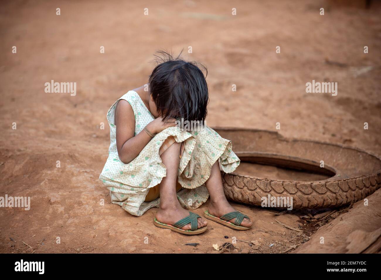 Asian girl A ragged dress sitting on the ground at a rural village ...