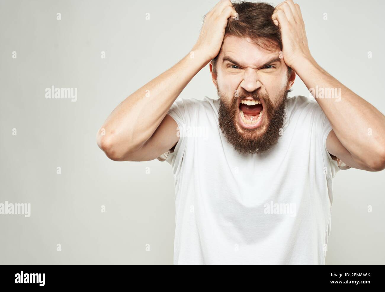 Aggressive man gestures with his hands on a light background stress ...