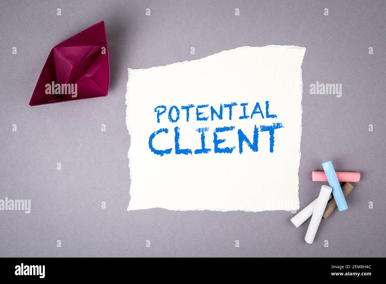 POTENTIAL CLIENT. Text on note sheet and paper boat on a gray ...
