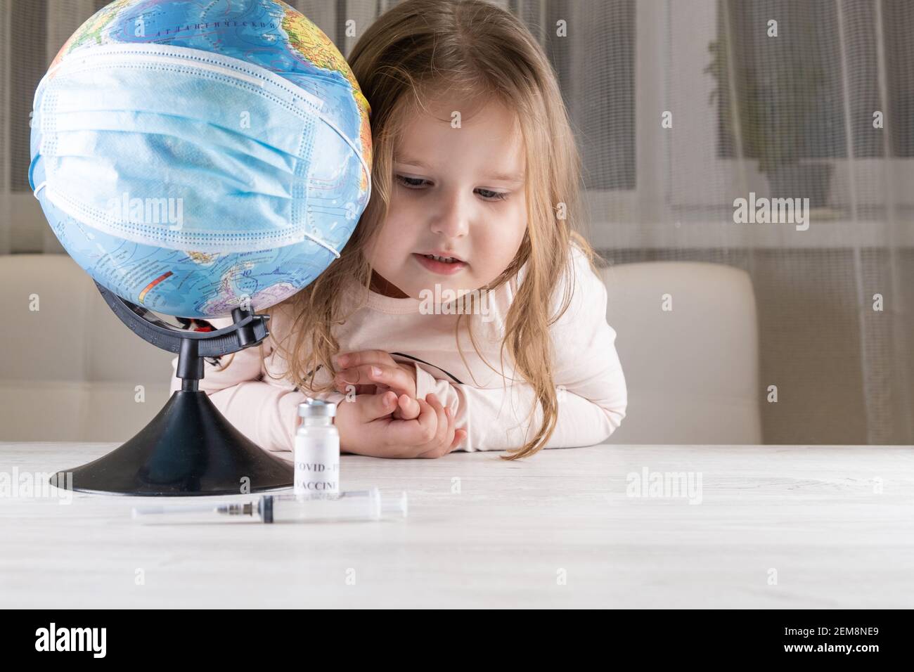 Little girl looks at vials with coronavirus vaccine, syringe and ...