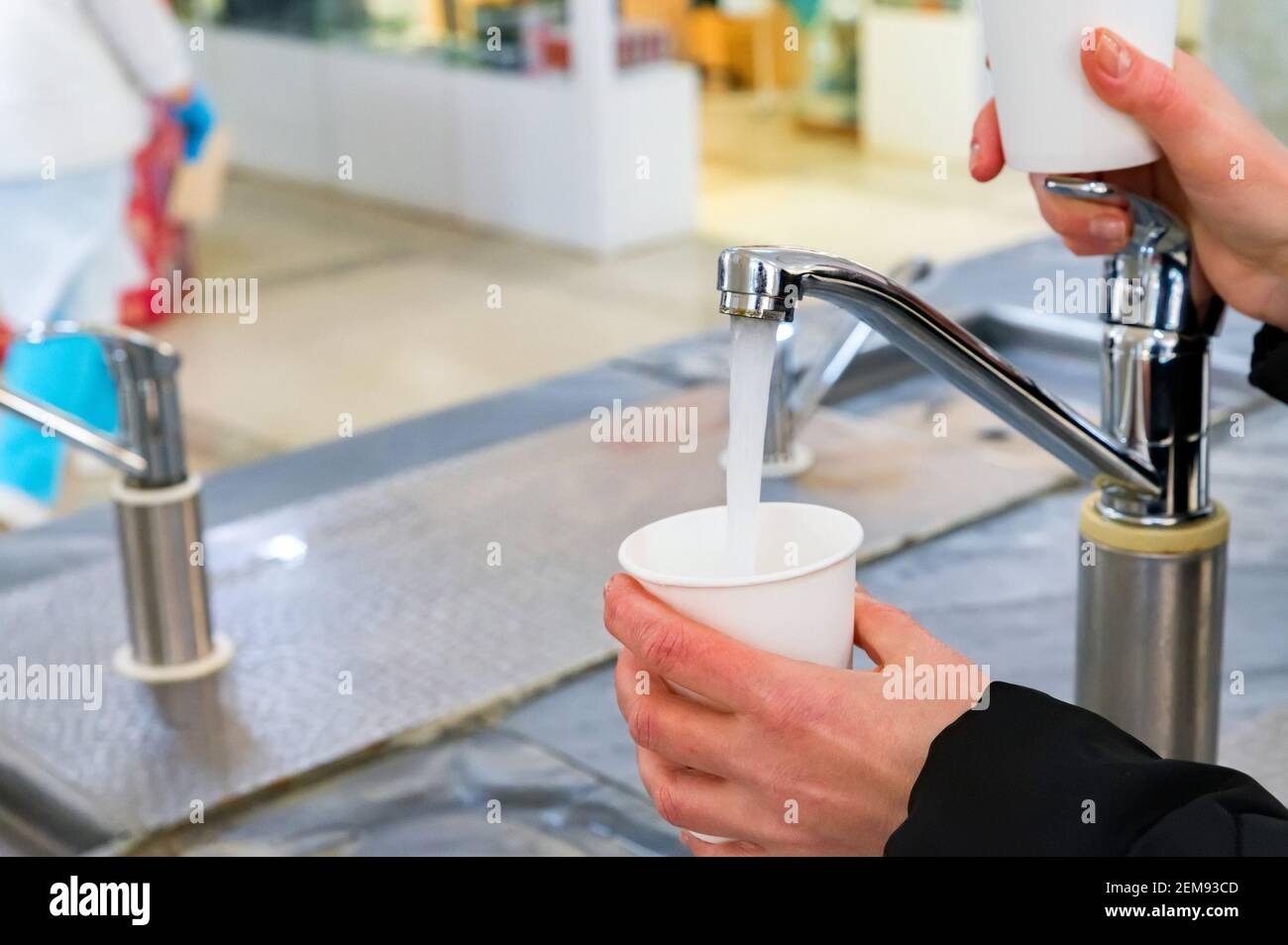 Close up male hand pouring mineral water in plastic glass in well-room Stock Photo - Alamy