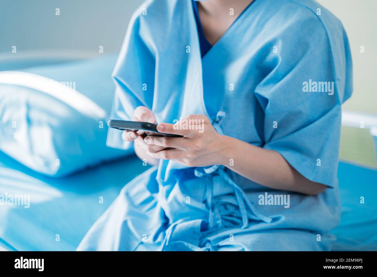 Closeup of hands of young female patient using smartphone to text and ...
