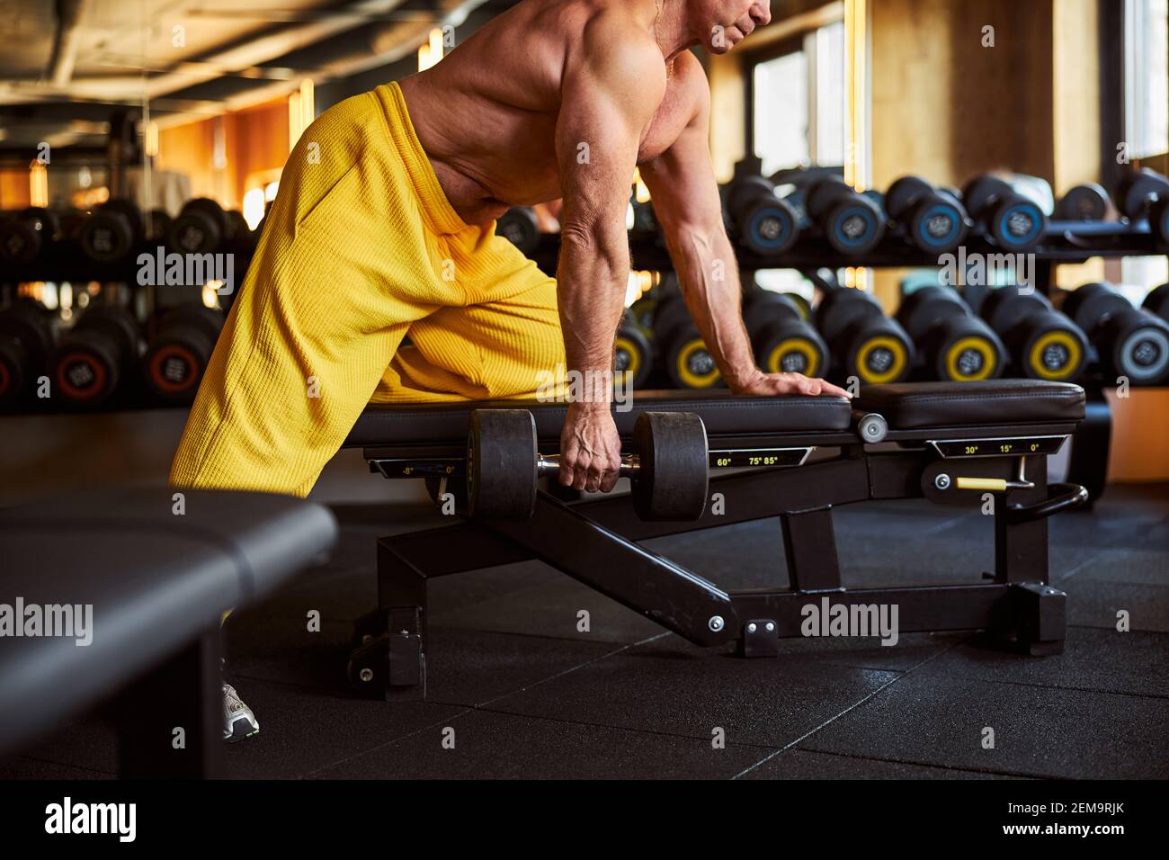 Muscular man performing a triceps kick-back exercise Stock Photo - Alamy