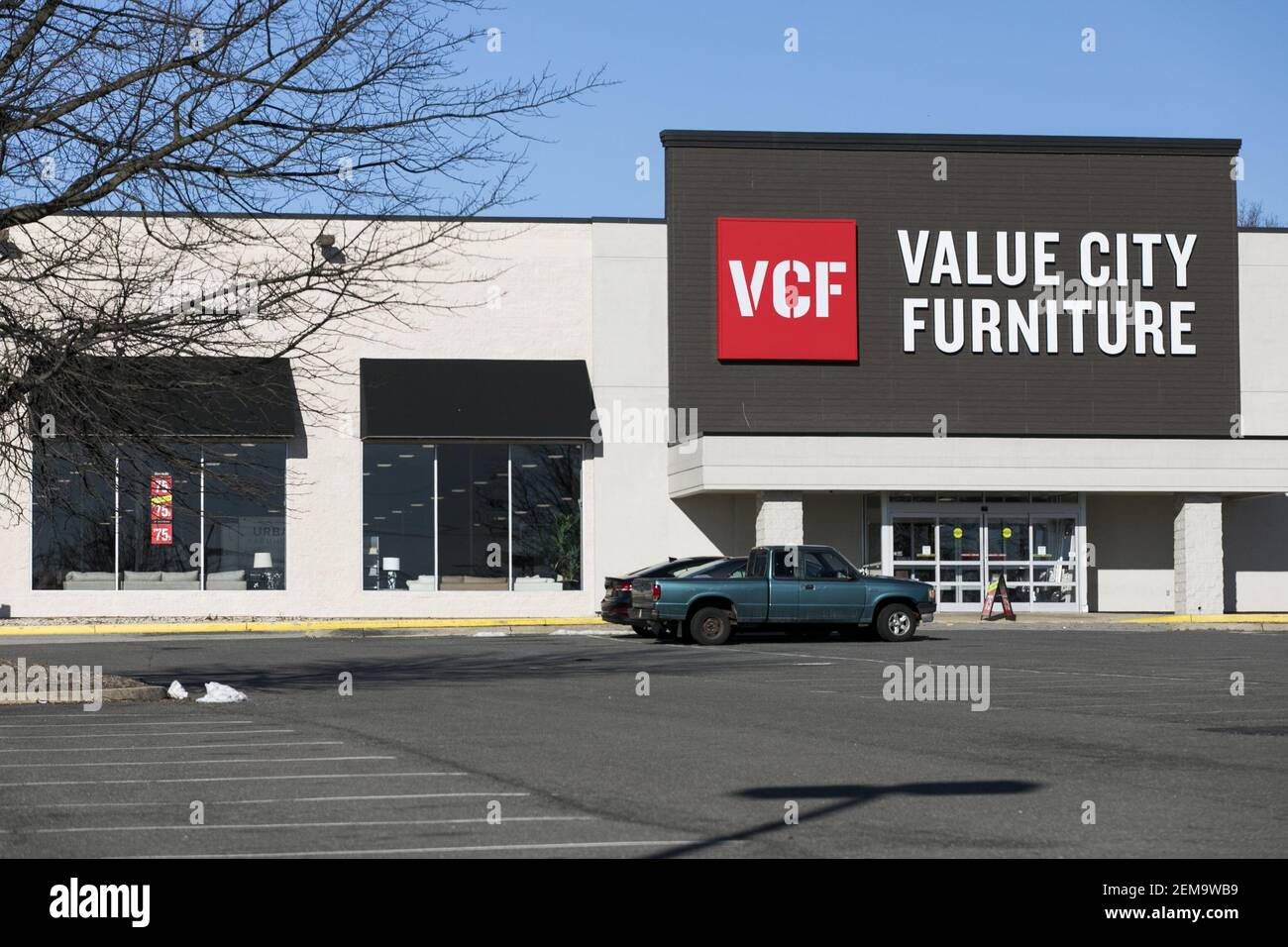 A logo sign outside of a Value City Furniture retail store location in ...
