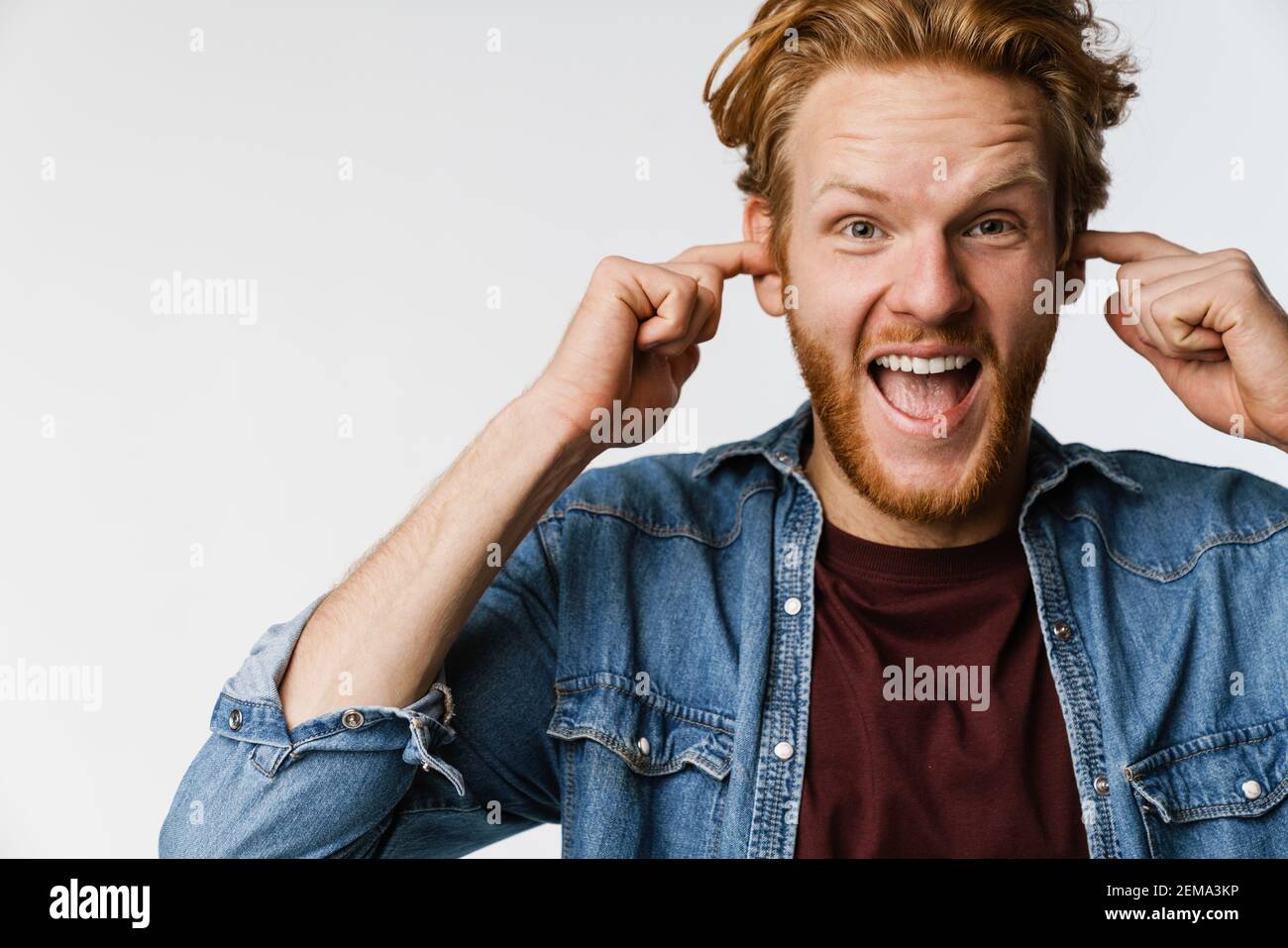 Excited handsome ginger guy exclaiming and plugging his ears isolated ...