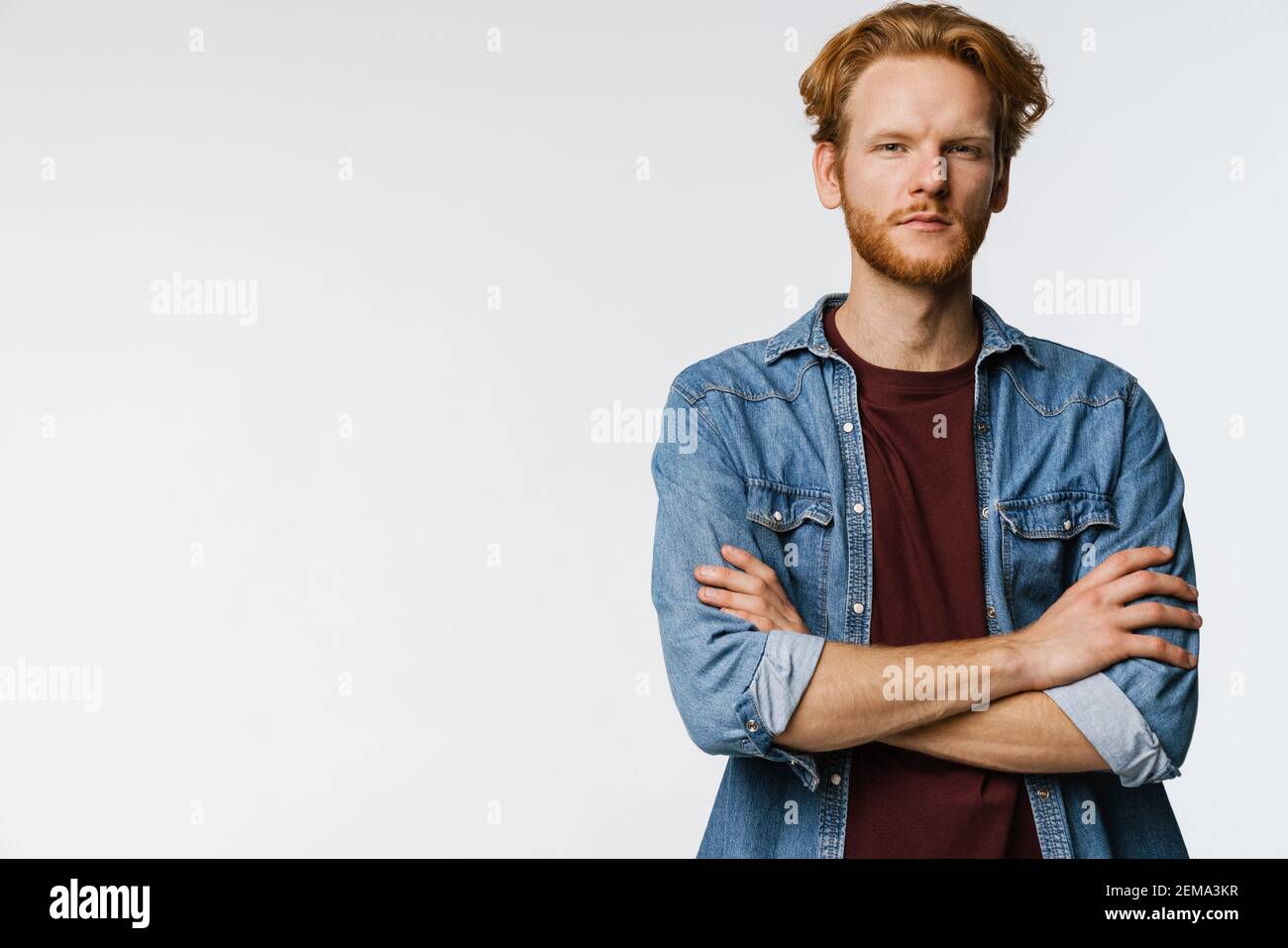 Serious handsome ginger guy posing and arms crossed isolated over white ...