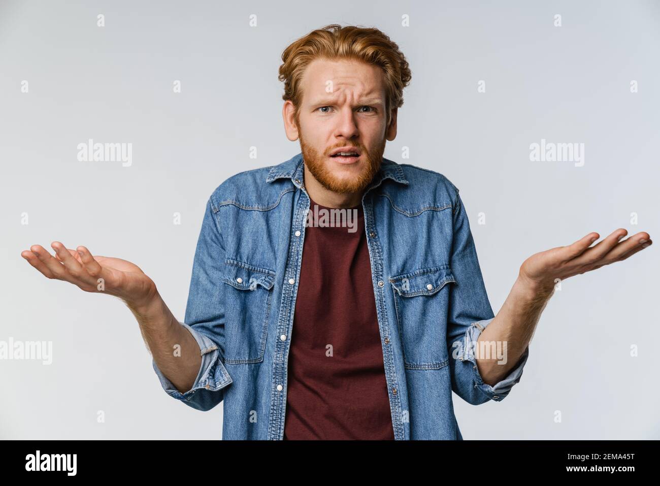 Confused unshaven redhead guy posing and looking at camera isolated ...