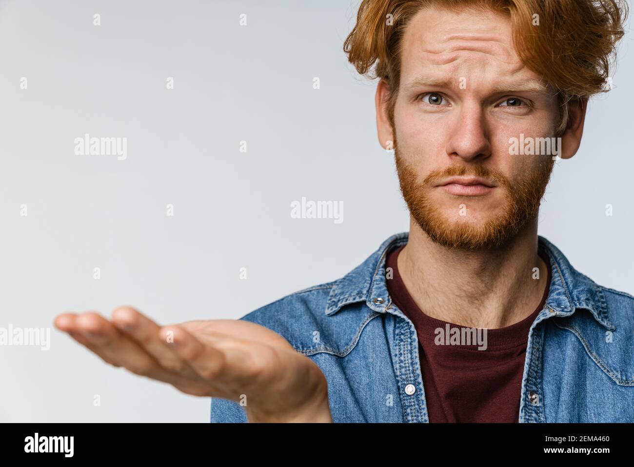 Confused handsome guy posing and holding copyspace isolated over white ...