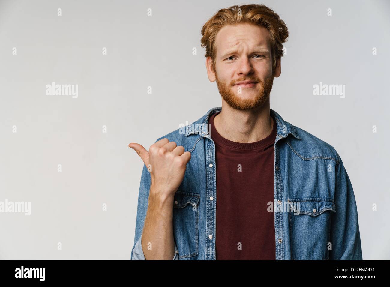 Confused handsome guy posing and pointing finger aside isolated over ...
