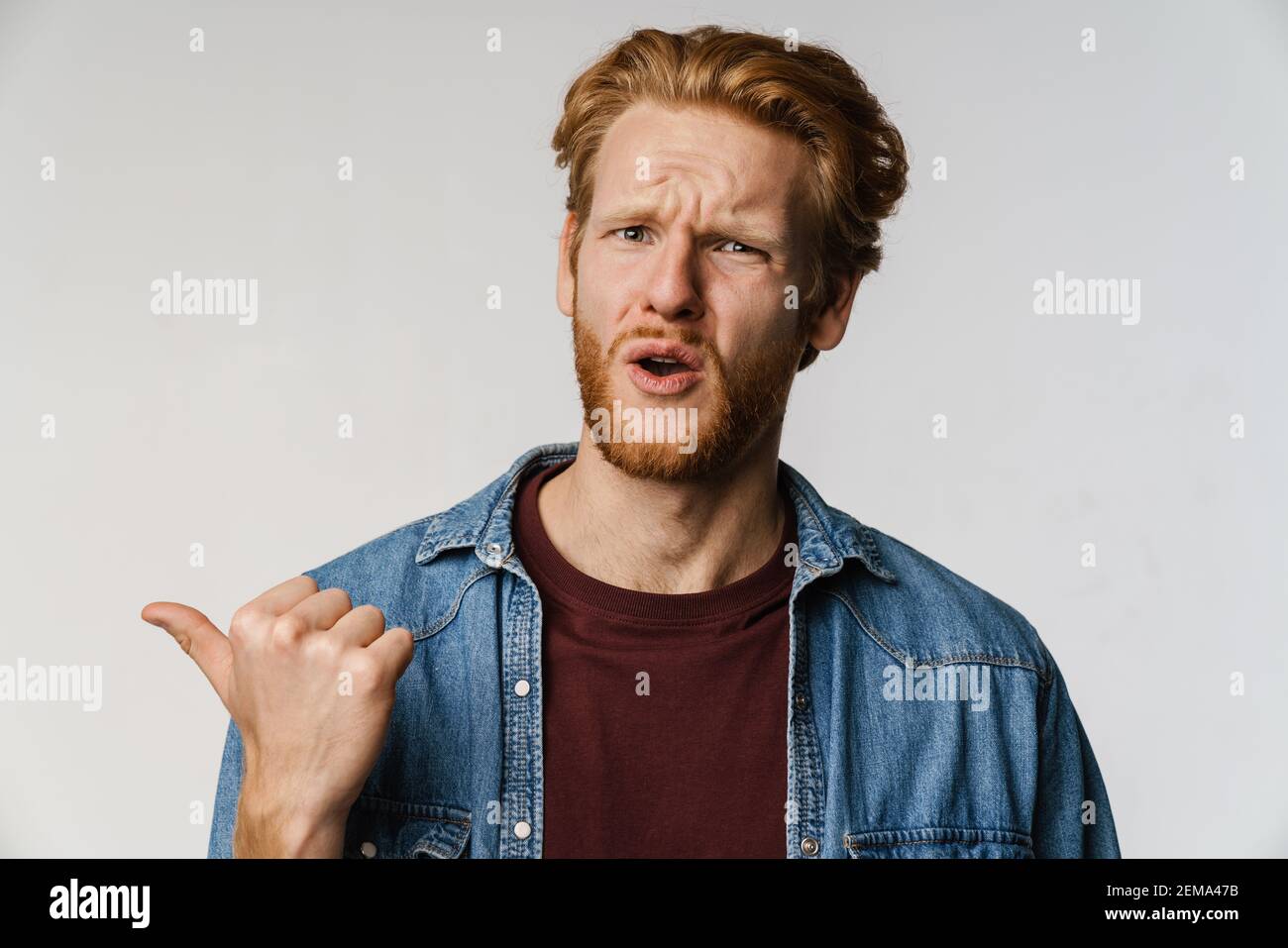 Shocked handsome guy posing and pointing finger aside isolated over ...