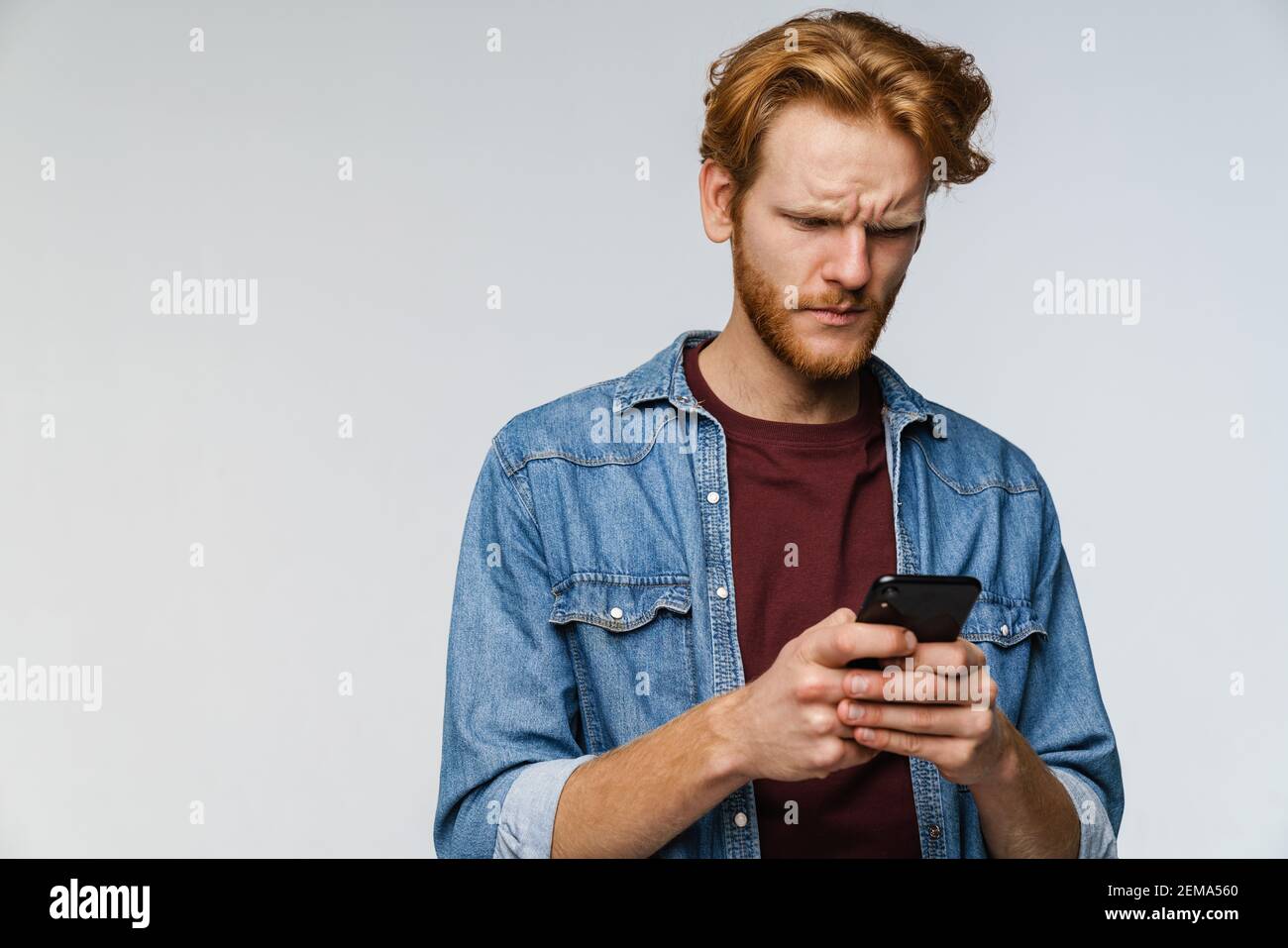 Brooding caucasian redhead guy posing and using cellphone isolated over ...