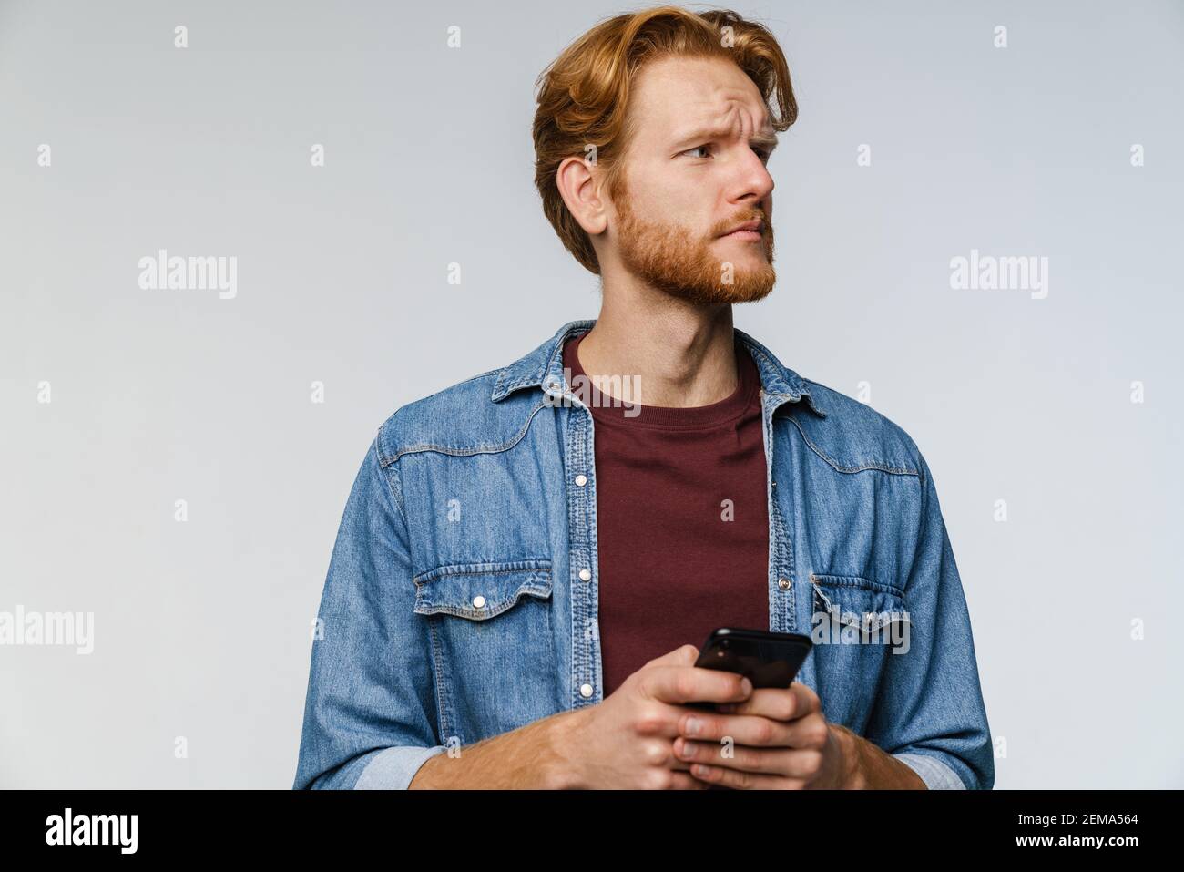 Brooding caucasian redhead guy posing and using cellphone isolated over ...