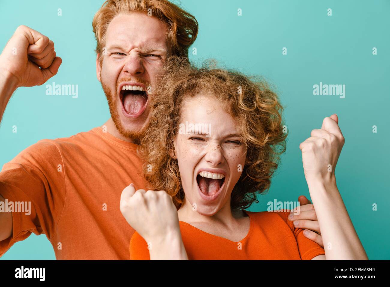 Young excited redhead couple screaming and making winner gesture ...