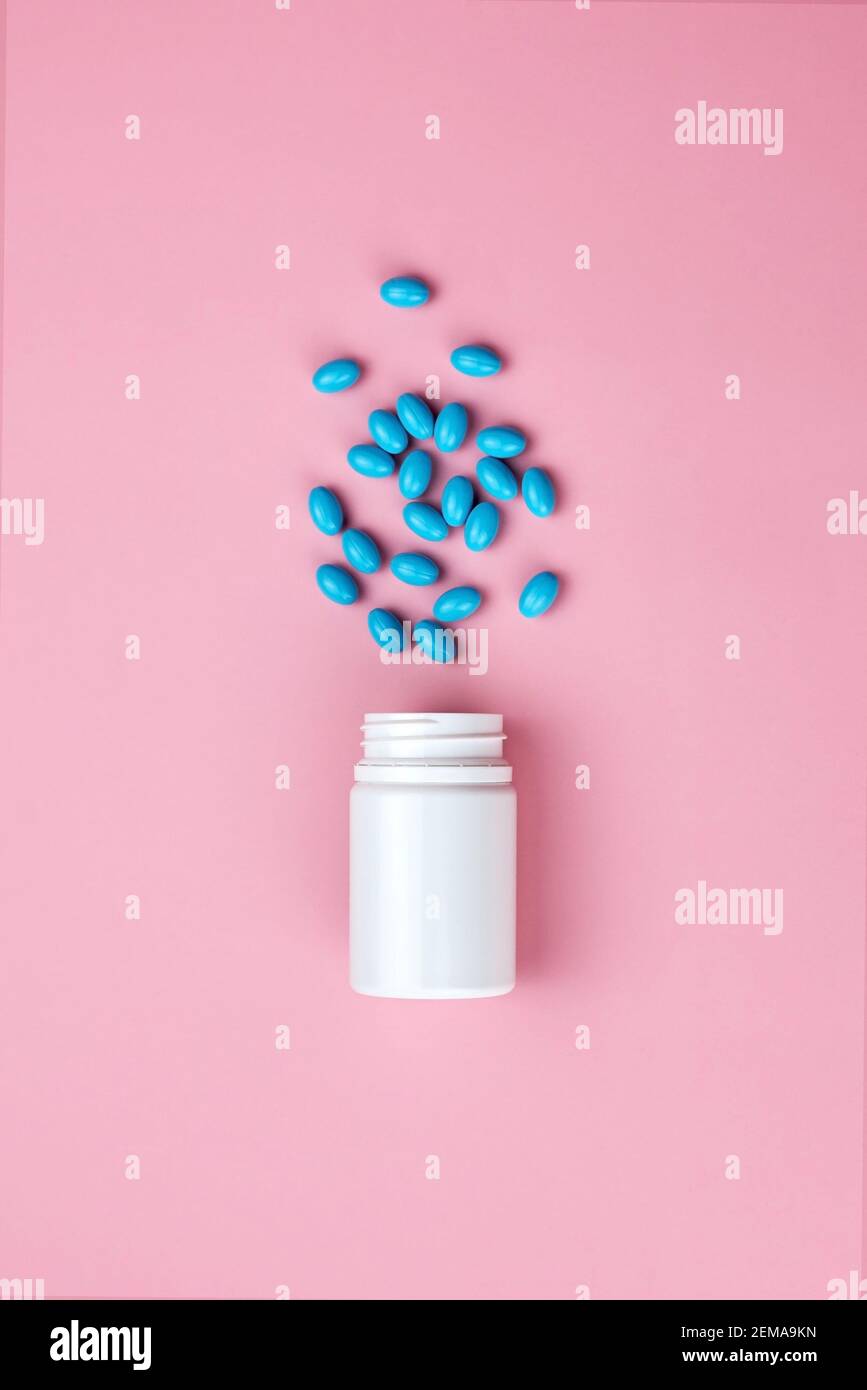 Blue pills poured from the jar on a pink background, the theme of ...