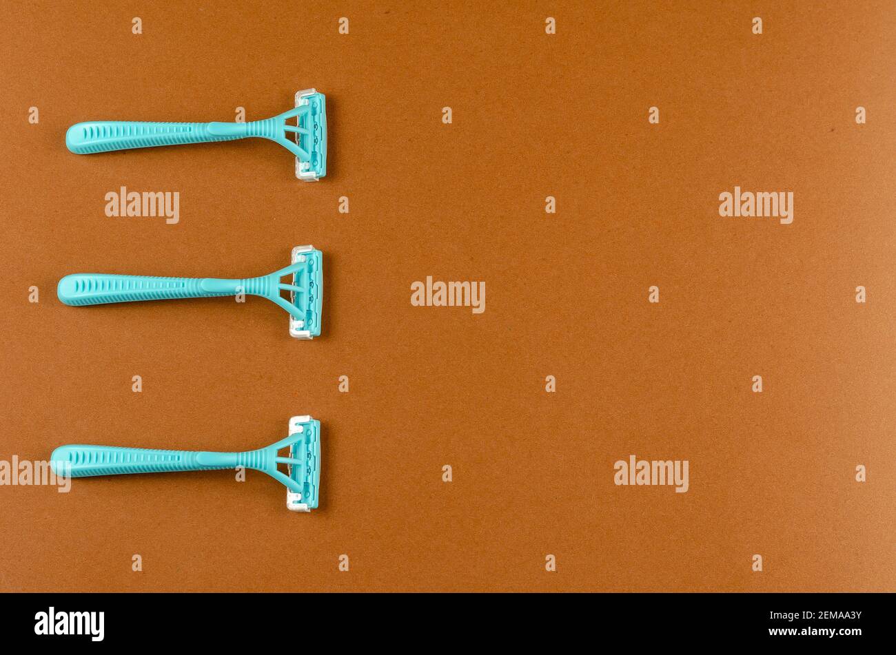 Blue plastic razors on a brown background. Three new razor. Top view ...
