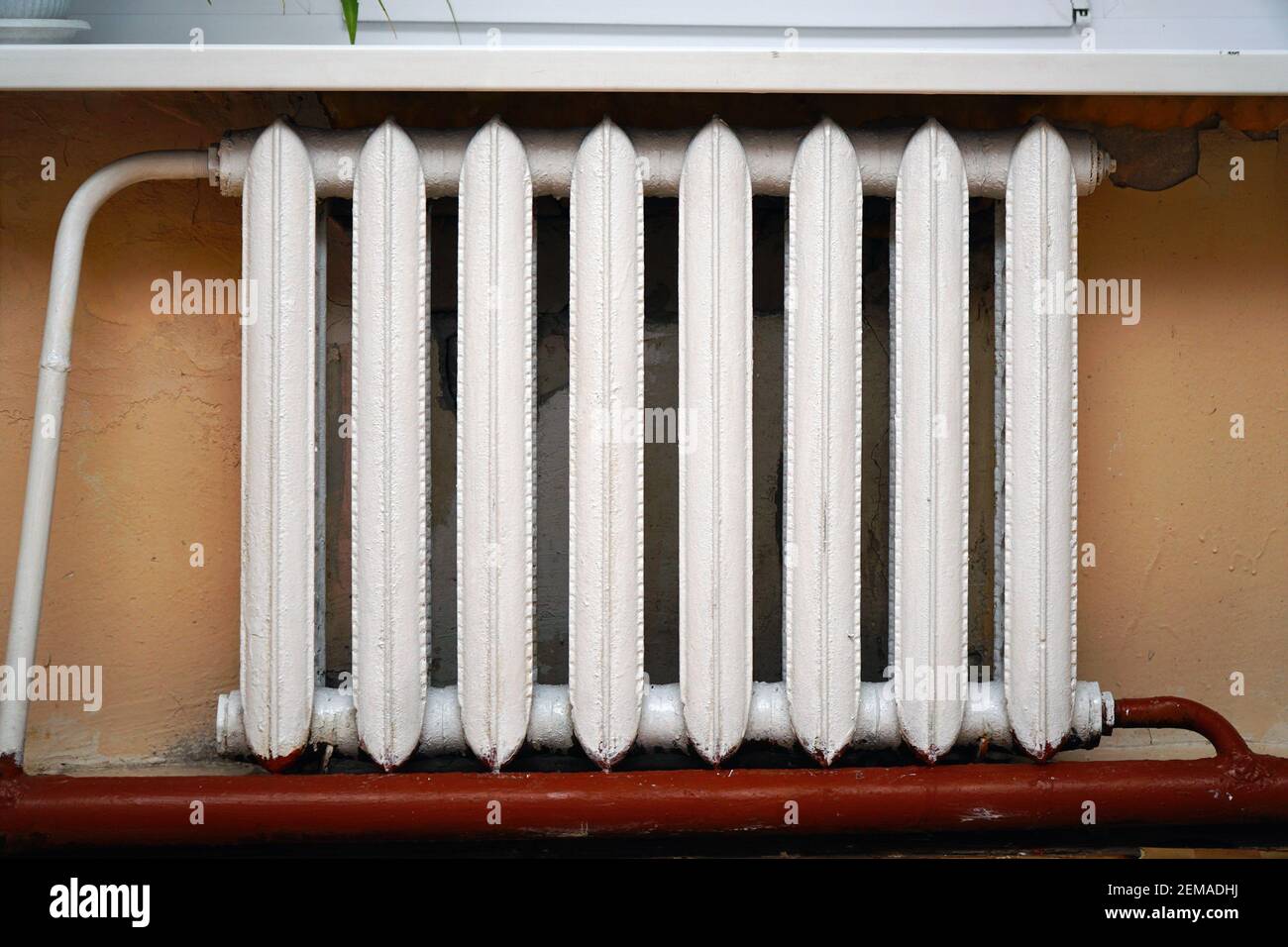 Old cast-iron radiator on the background of gray wall. Heating battery ...