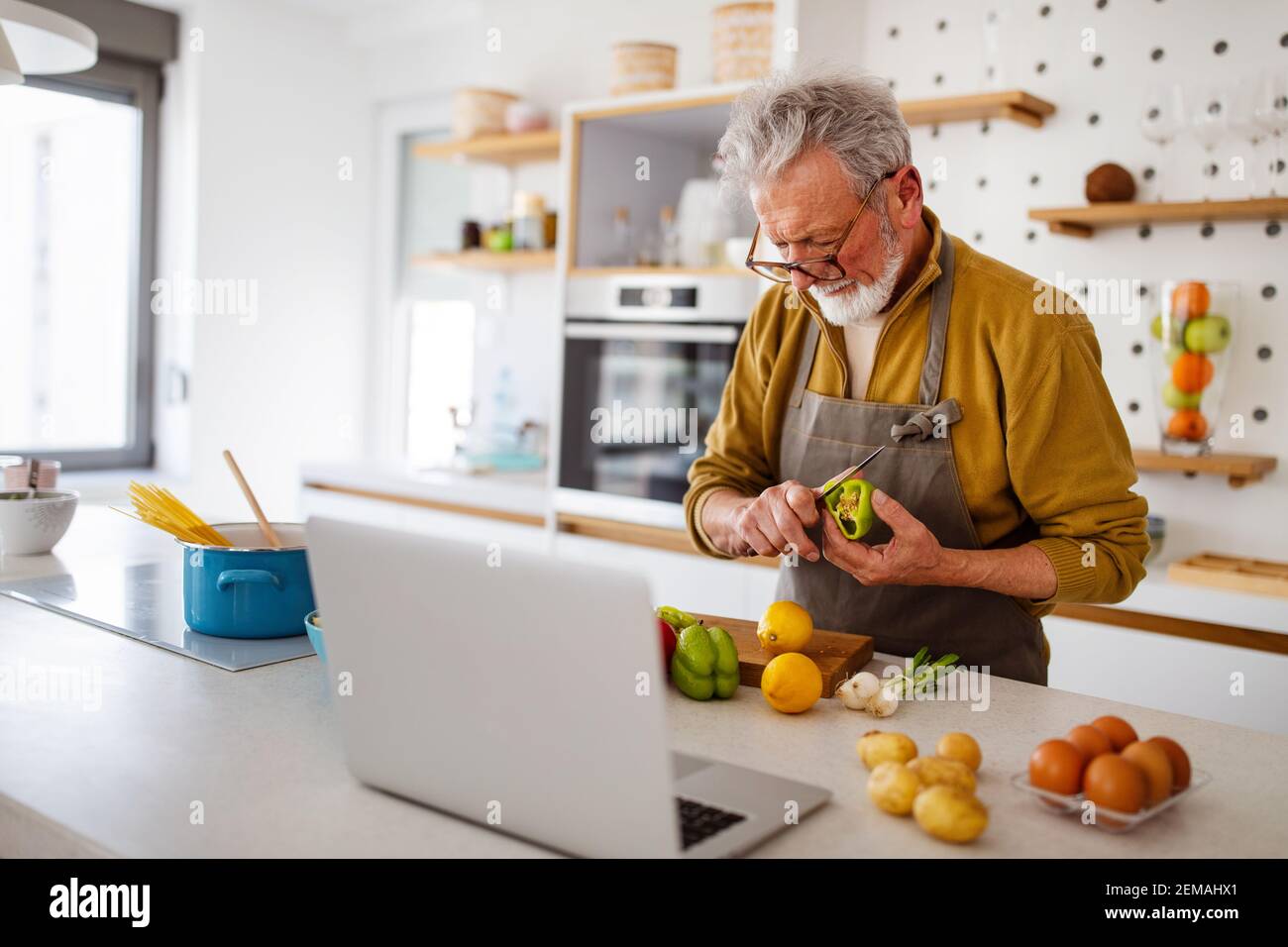 Happy retired senior man cooking in kitchen. Retirement, hobby people ...