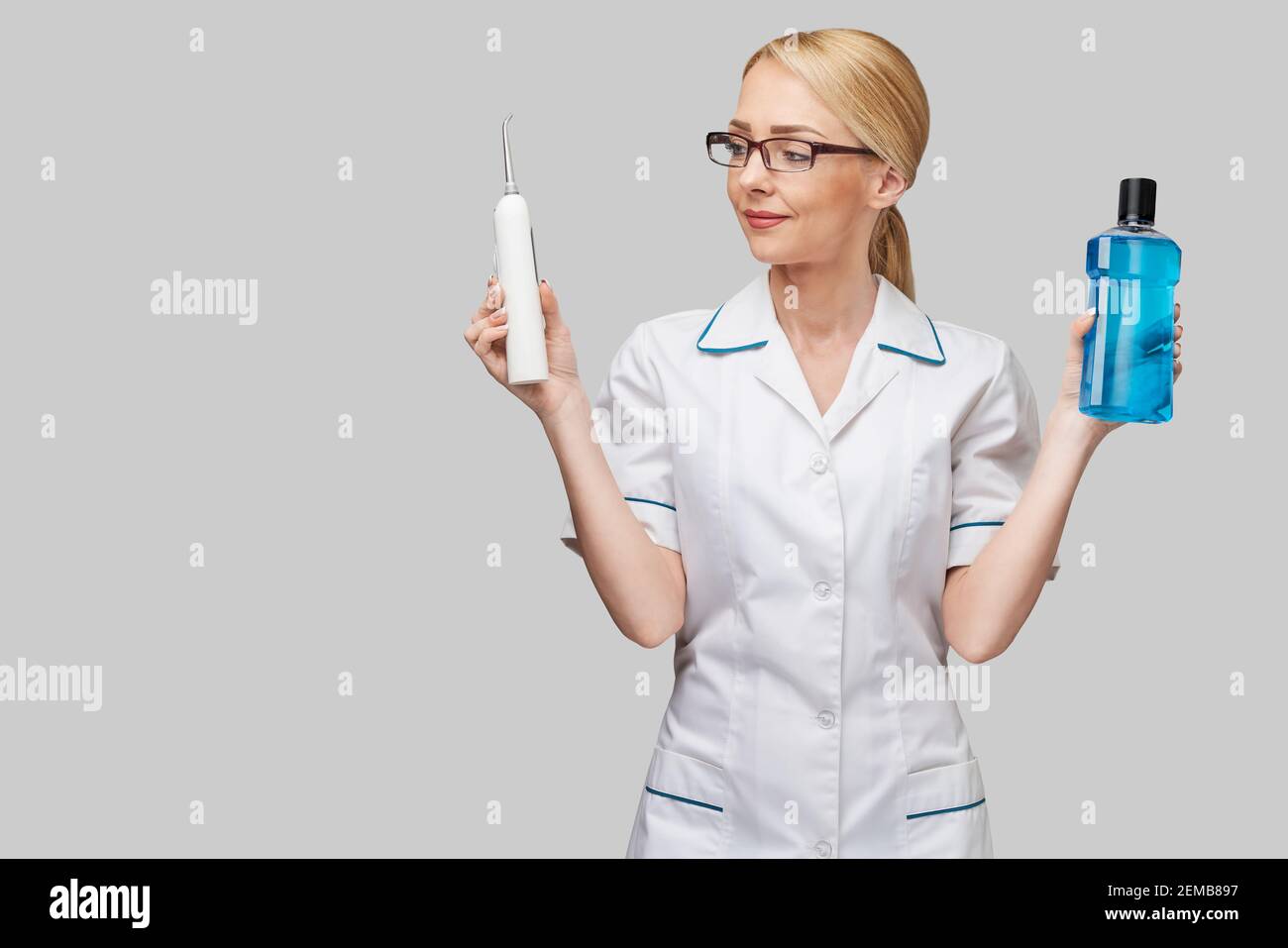 woman dentist doctor holding bottle of mouthwash and irrigator standing ...