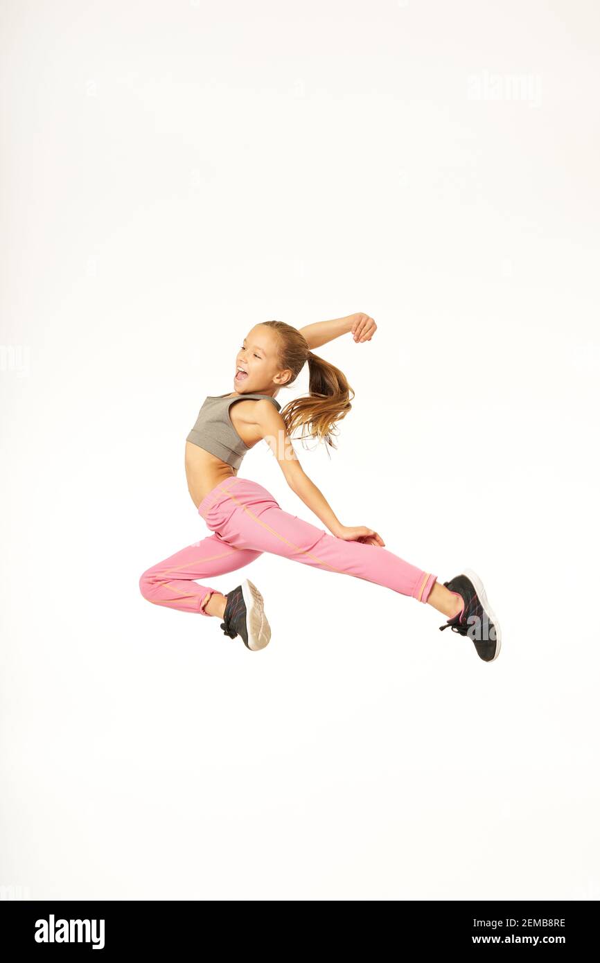 Adorable female child looking away and laughing while jumping and ...