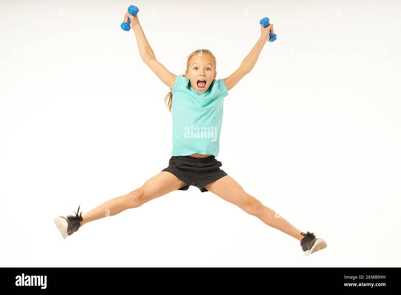 Cute girl in sportswear jumping and screaming while doing exercise with ...