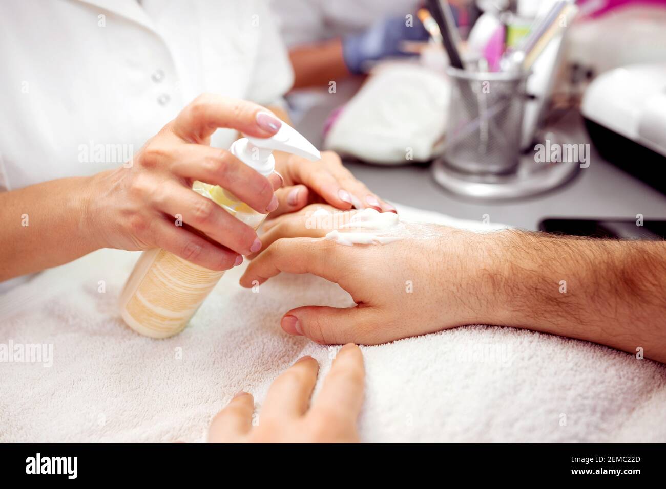 Applying of skin lotion in a manicure treatment, hand beauty treatment ...