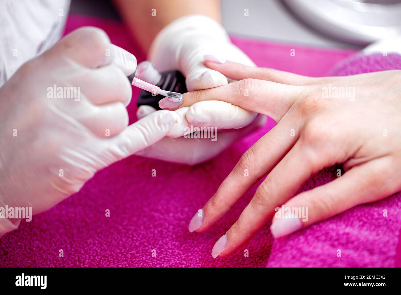 Experienced hands of a manicurist doing nail polishing making nails of ...