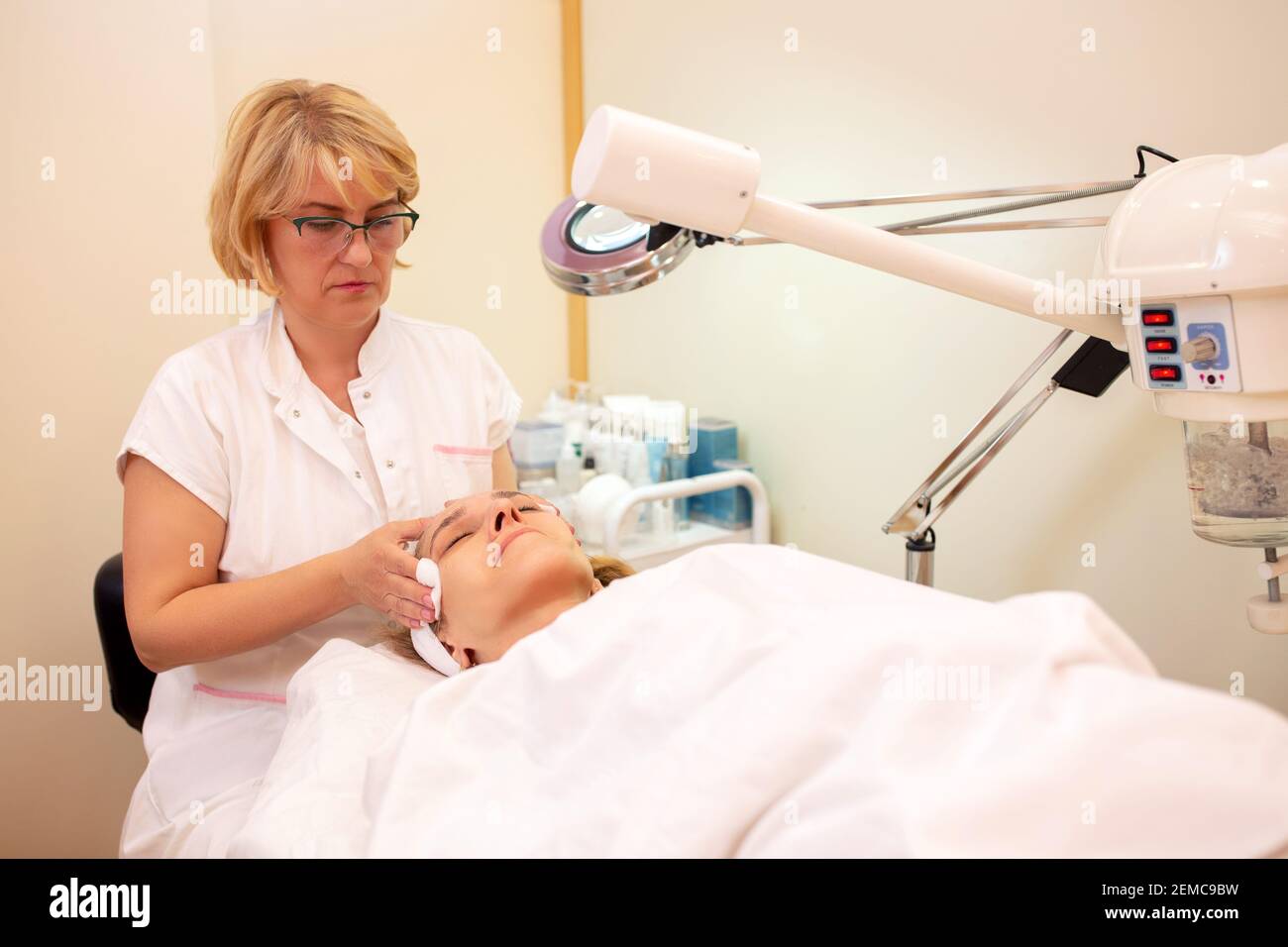 Gentle and kind cosmetician keeping her clients facial skin revitalized ...