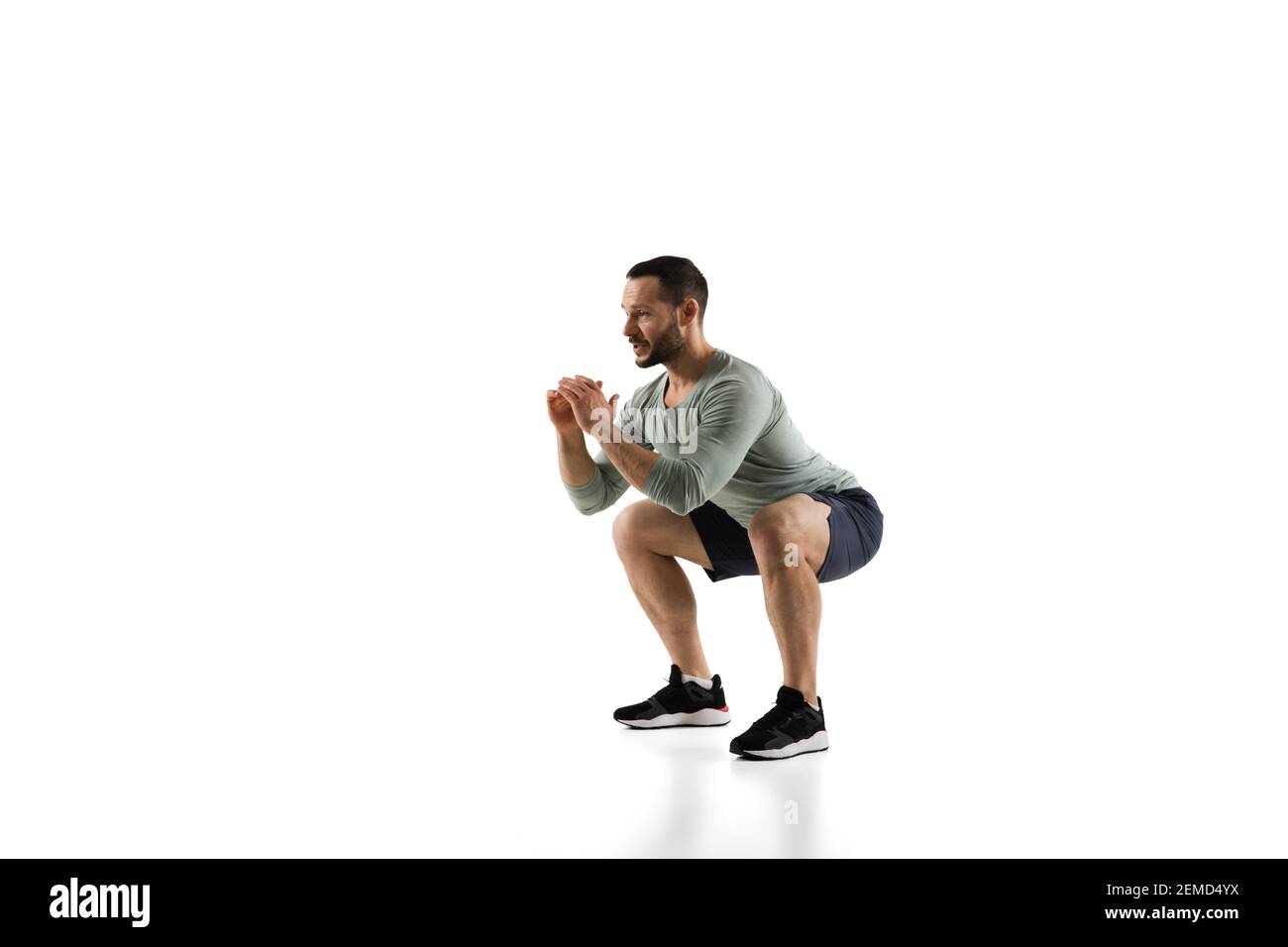 Squats. Young caucasian male model in action, motion on white ...