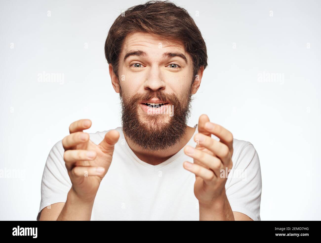Portrait of an energetic man in a white t-shirt on a light background ...