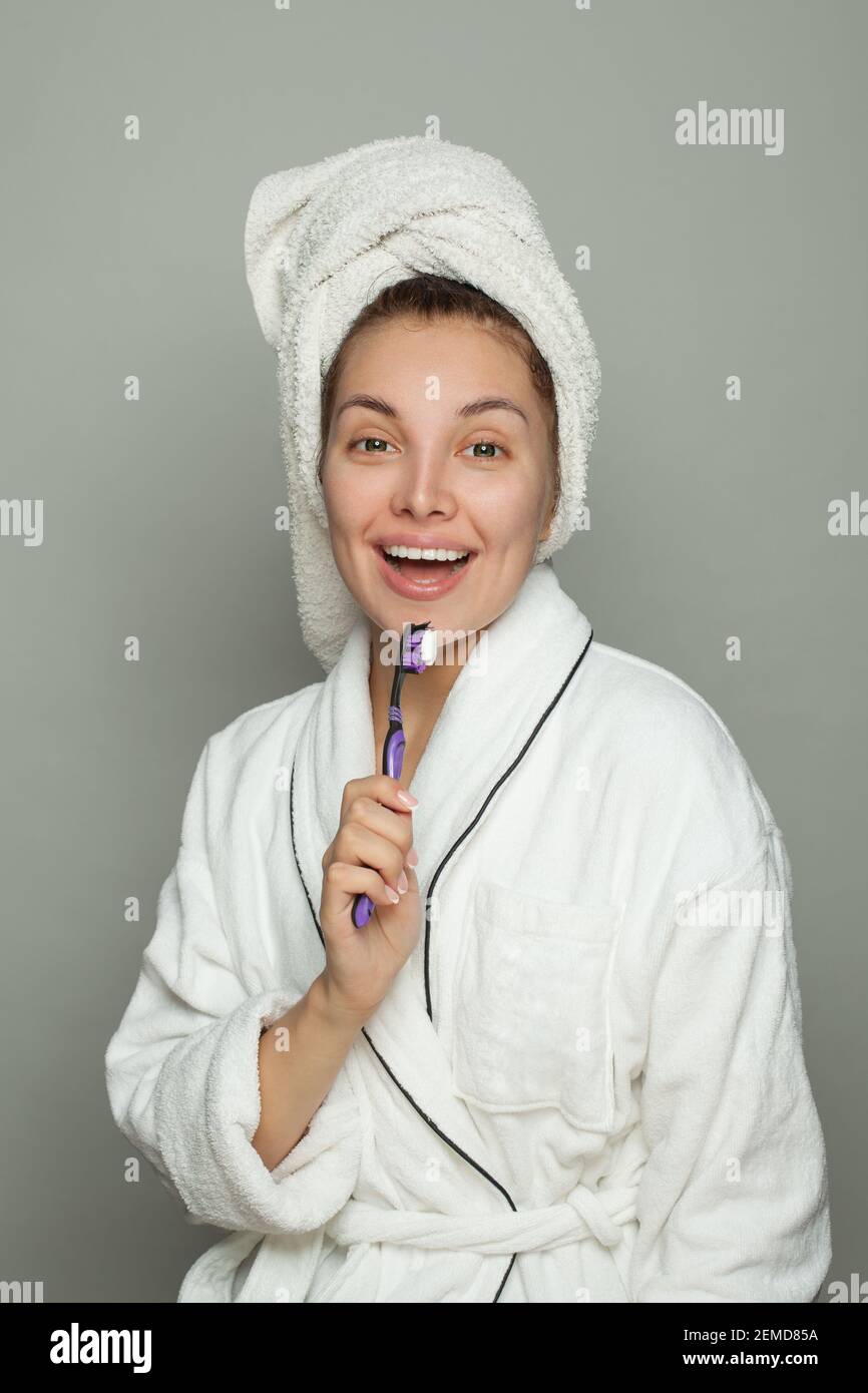 Happy spa woman brushing her teeth and singing on white background ...