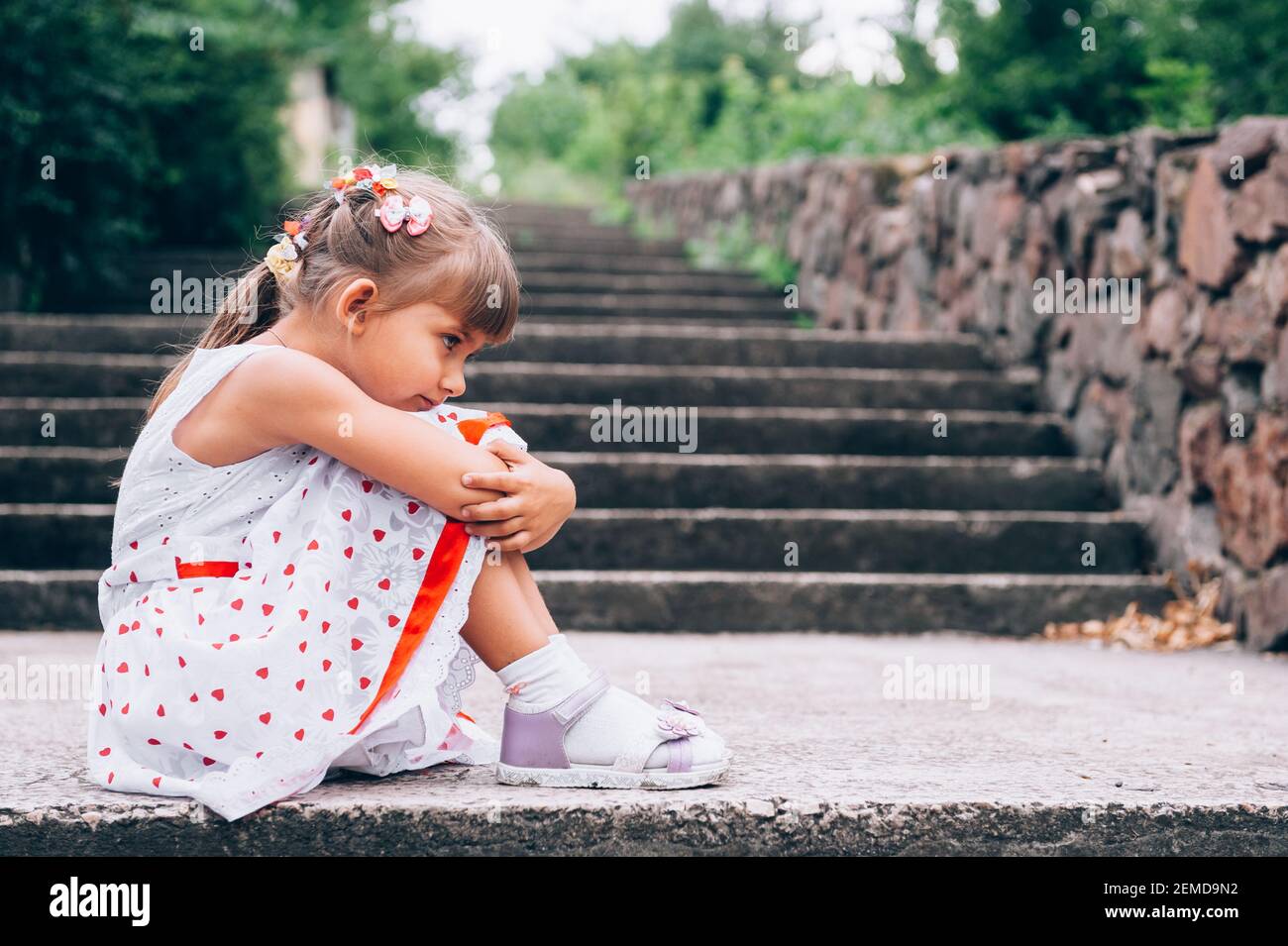 Little girl is sitting on the stairs Stock Photo - Alamy