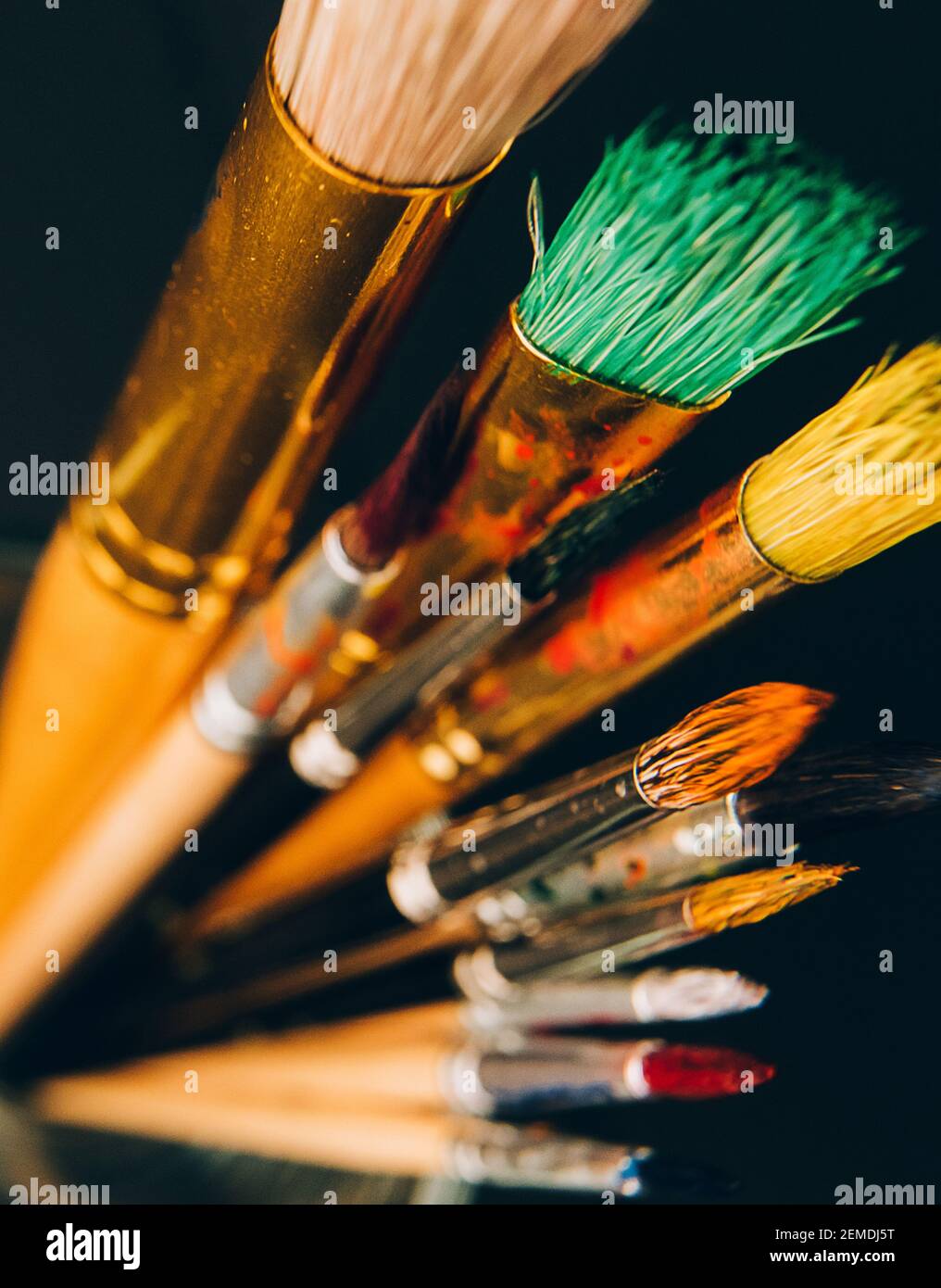 Artistic brushes with traces of paint on a dark background with a ...