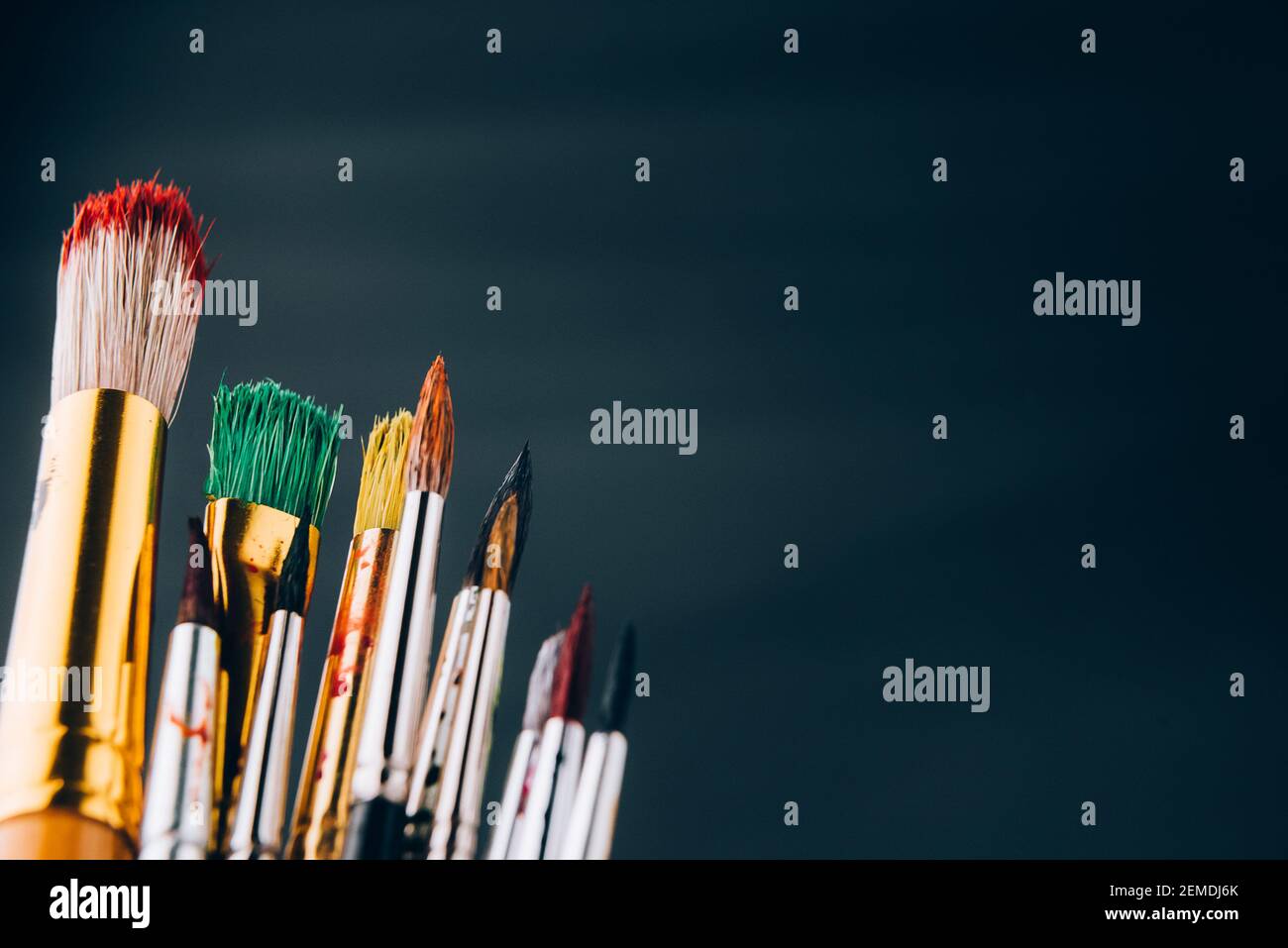 Artistic brushes with traces of paint on a dark background with a ...